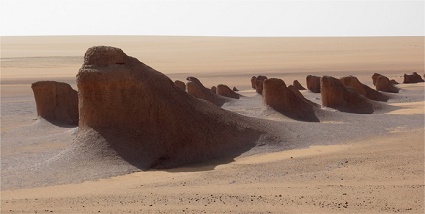 The photograph below shows solid bedrock sticking out above the desert ...
